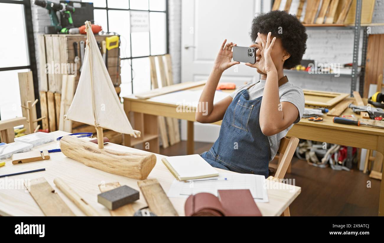 African american woman captures memories with her phone in a creative workshop setting Stock ...
