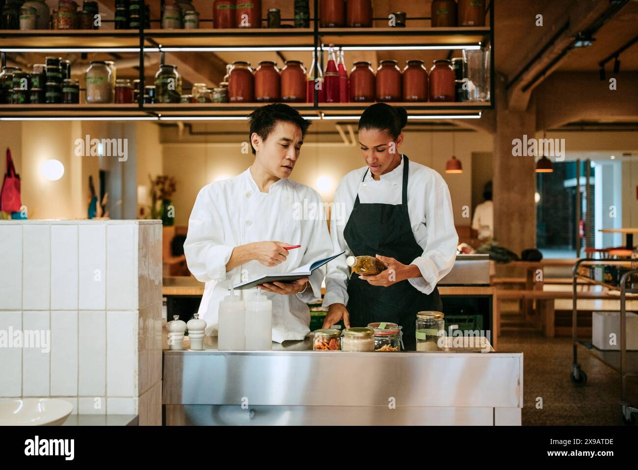 Focused male and female chef discussing while taking inventory while ...