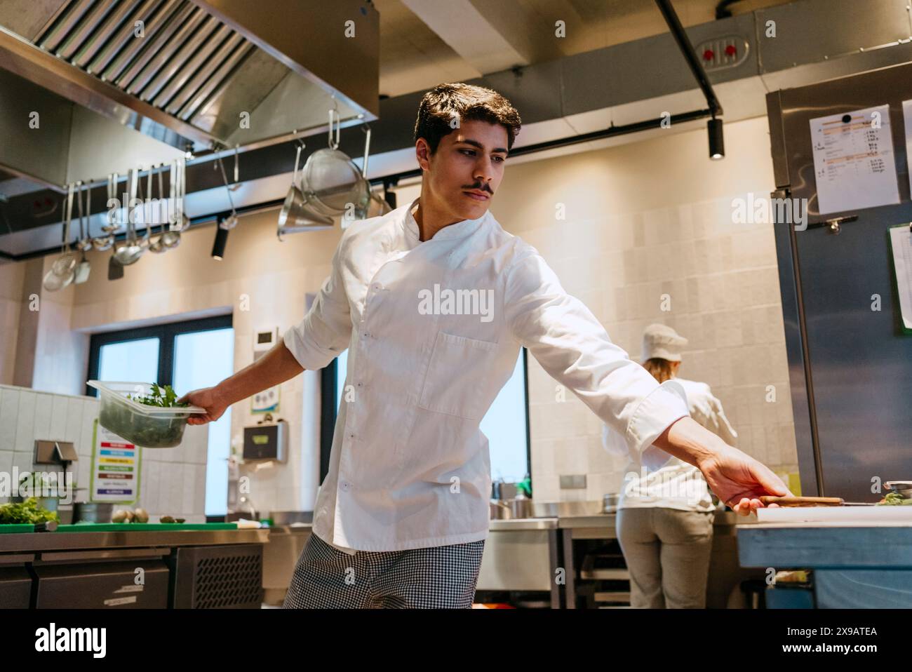 Male chef with mustache multi-tasking in commercial kitchen Stock Photo ...