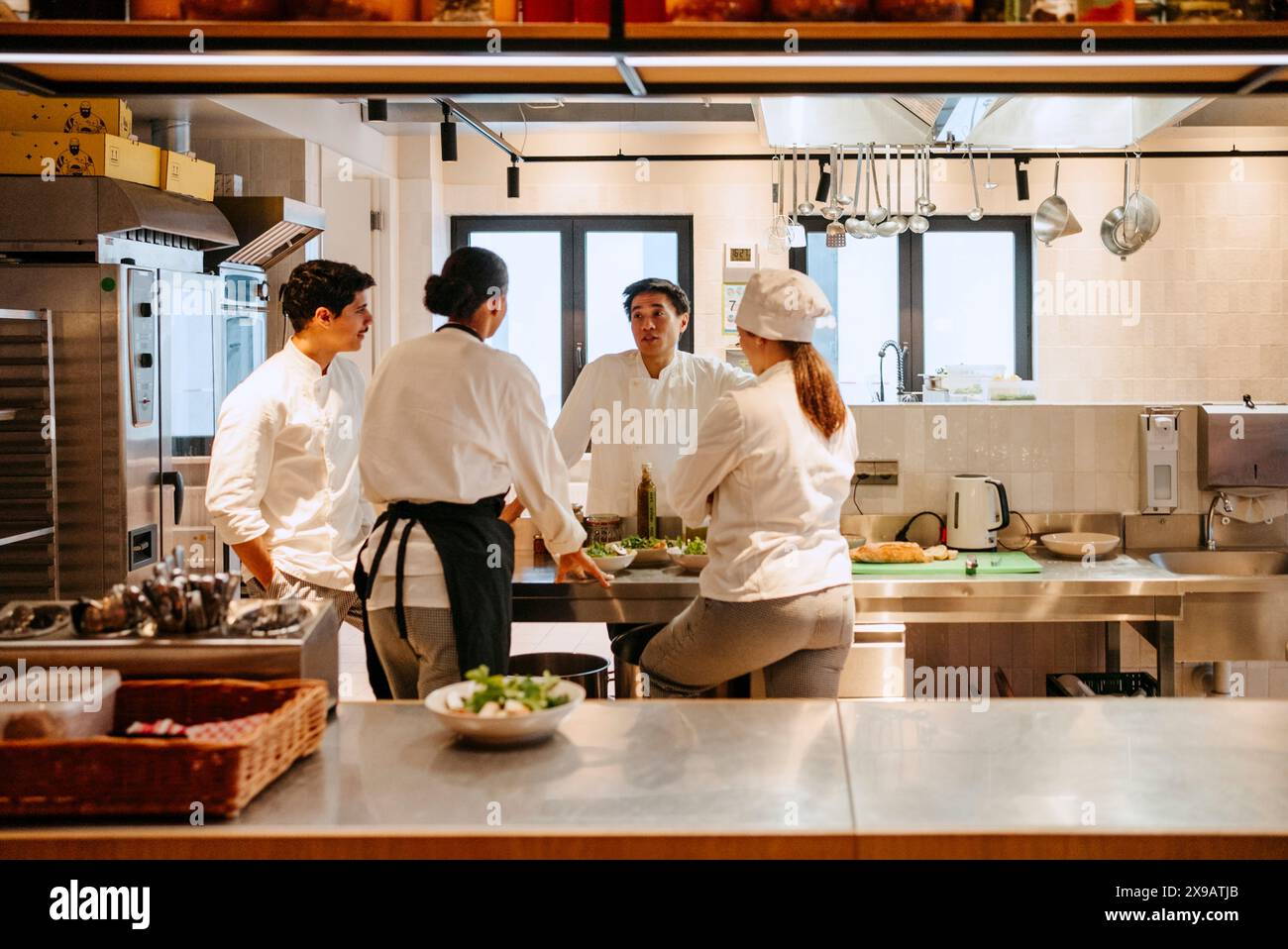 Male and female chefs discussing while standing in commercial kitchen ...