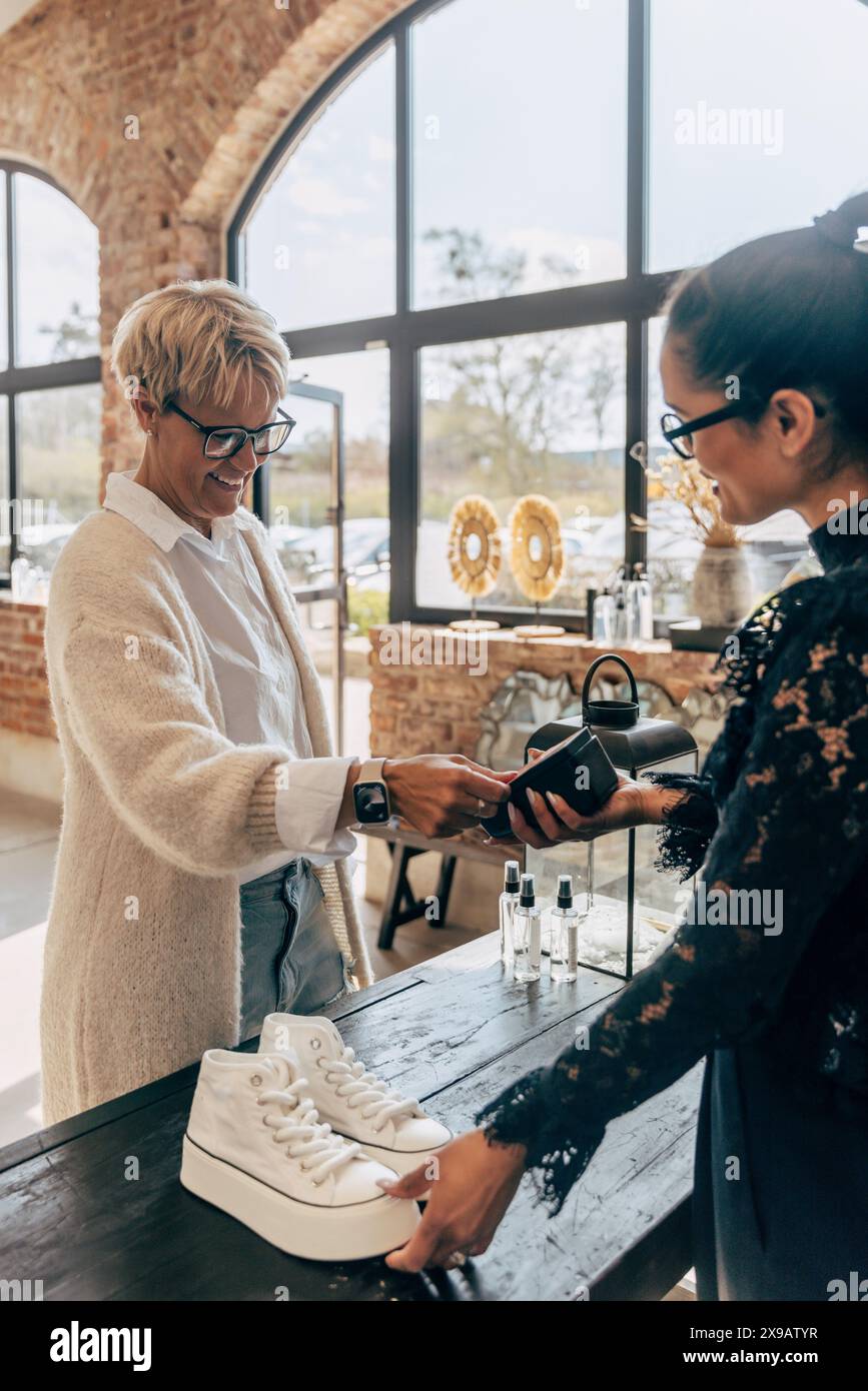 Female customer paying via tap to pay method at checkout in store Stock ...