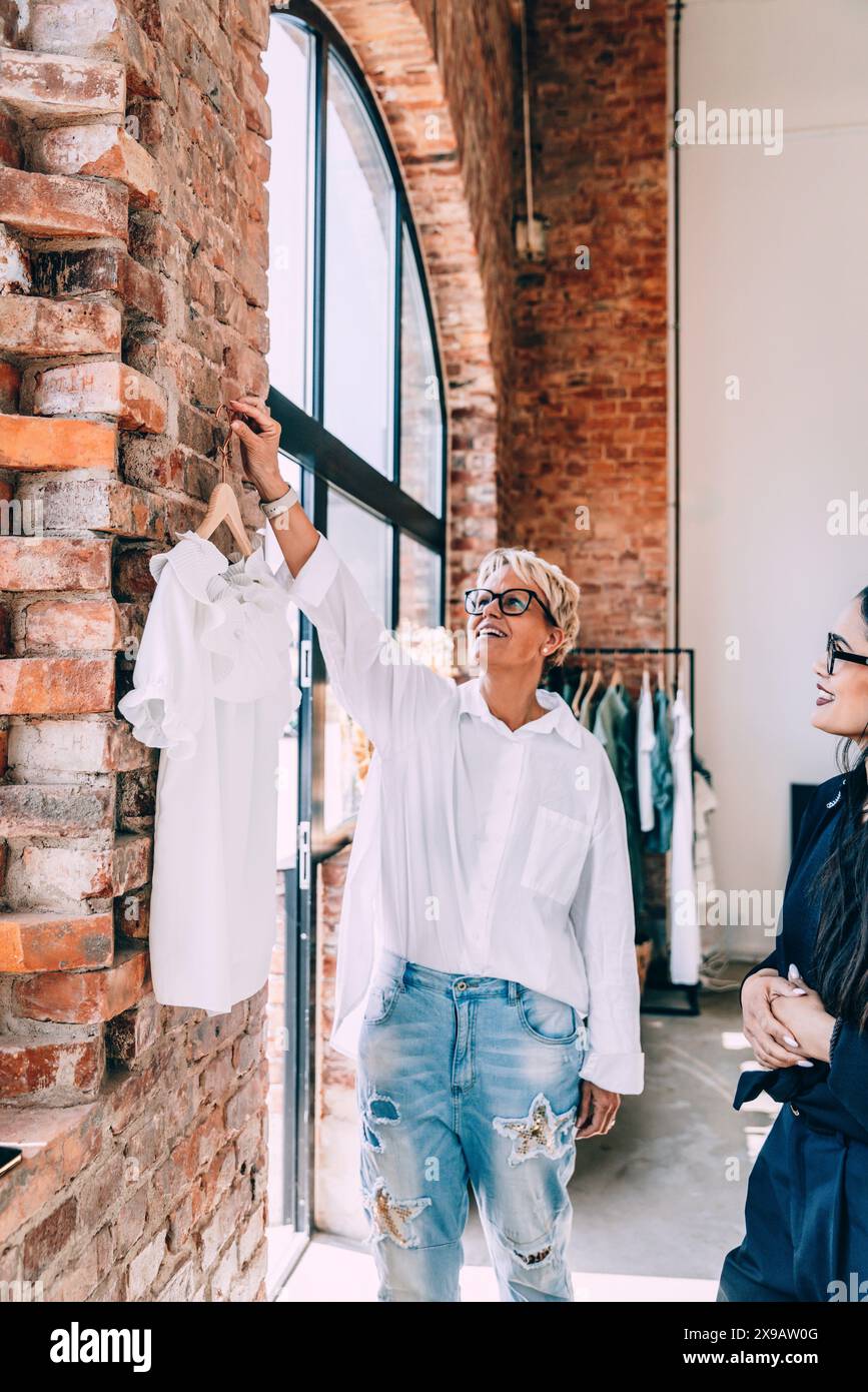 Female owner hanging top on brick wall while standing with customer in ...