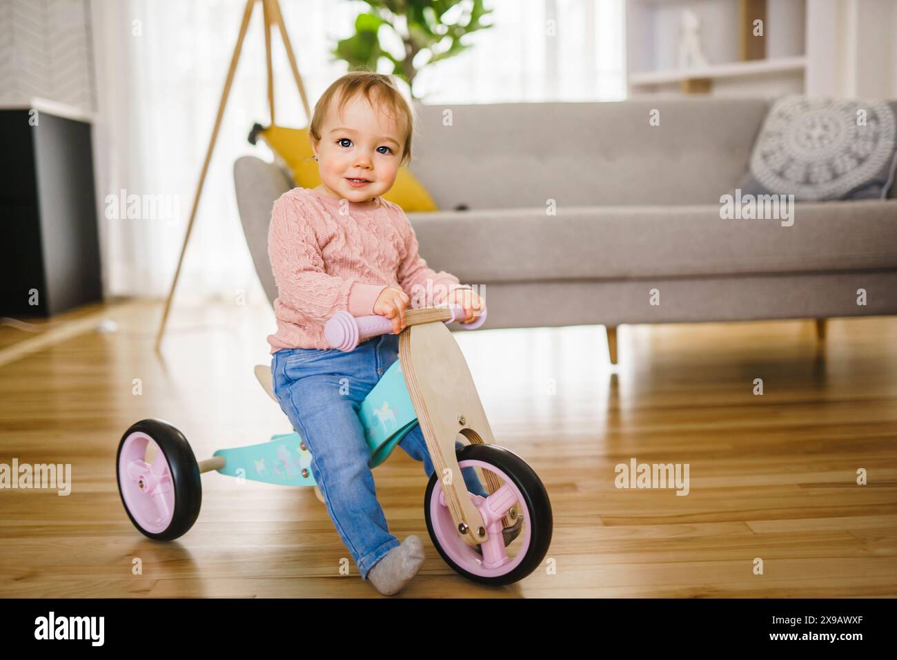 Adorable little baby girl learning to balance on her first bike at home ...