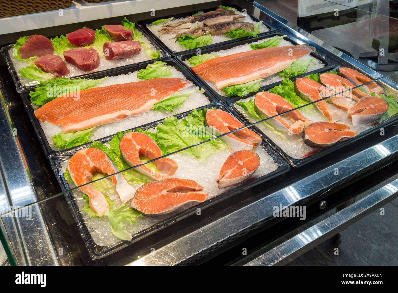 Selection of fresh fish fillets and steaks on ice at a seafood counter ...