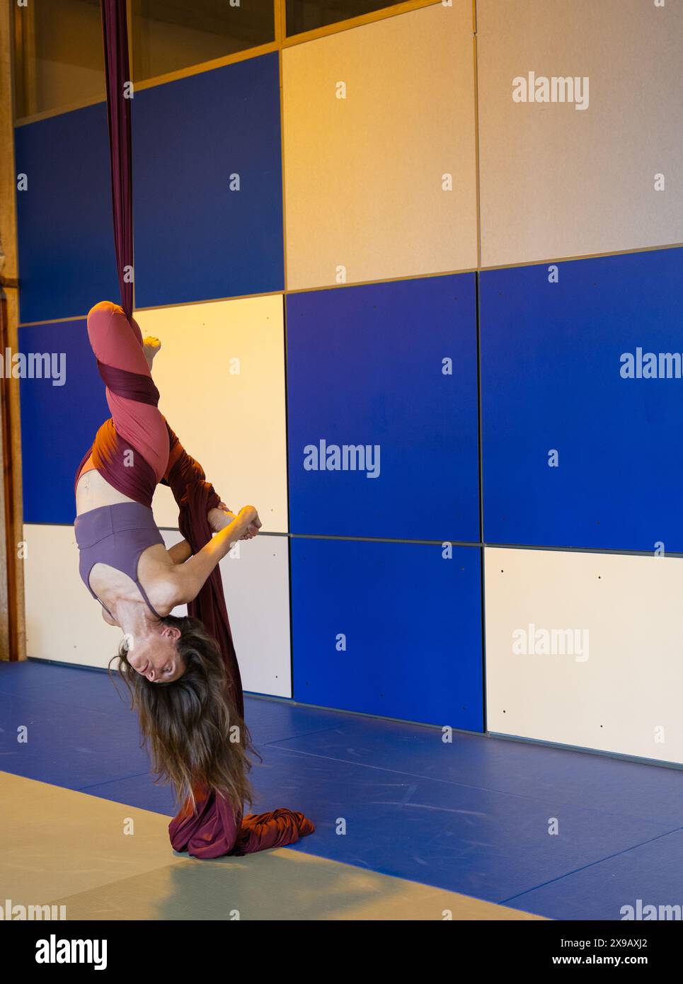 Athletic woman hanging upside-down during an aerial acrobatics routine ...
