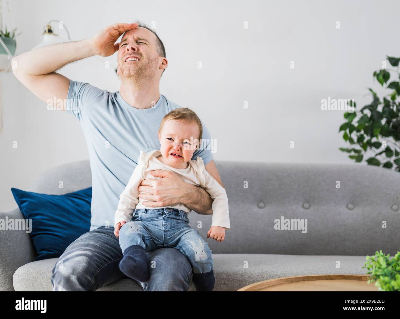 Man holding a screaming baby the father have headache Stock Photo - Alamy