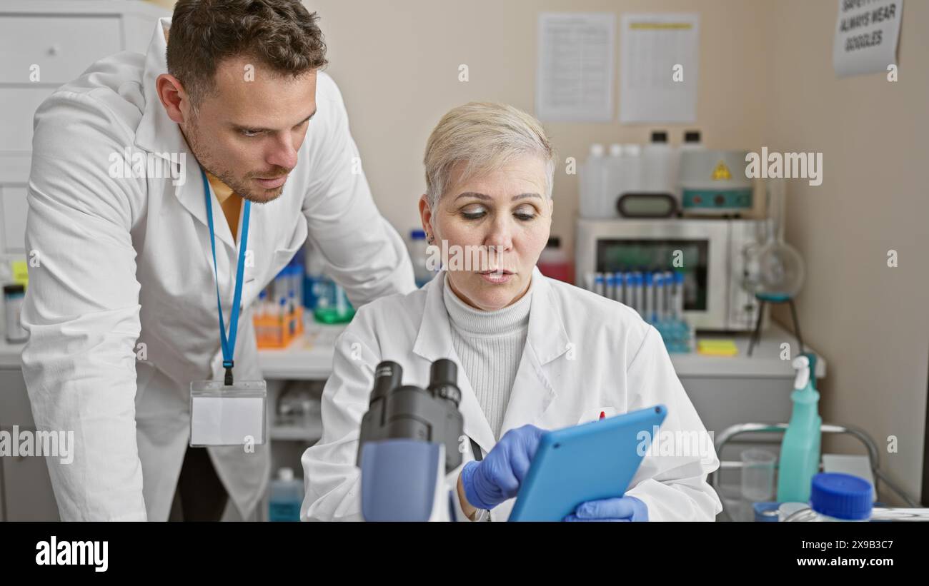 Man and woman, both scientists, closely examining data on a tablet in a ...