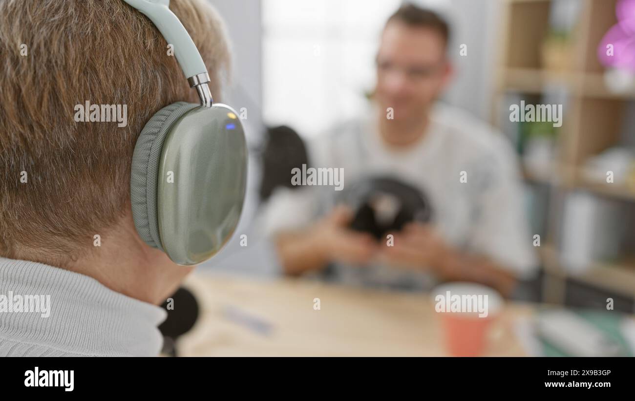 A woman with headphones interviews a blurred man on a podcast in a ...