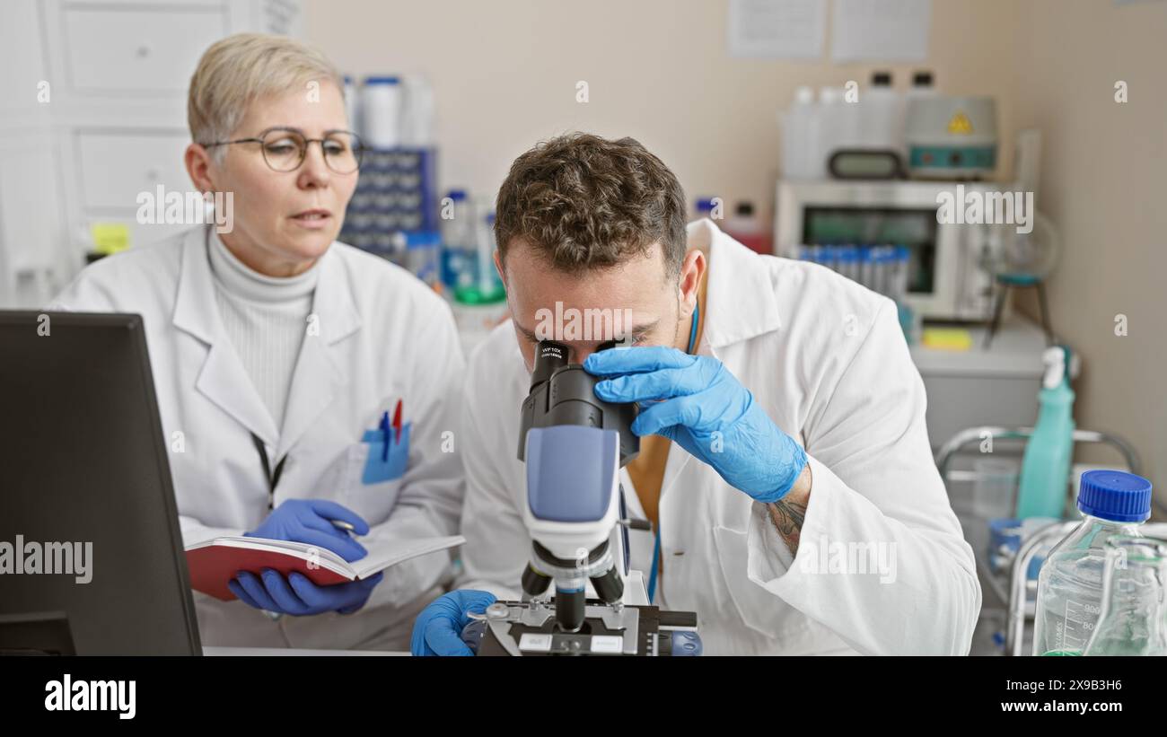 A woman and man, scientists, work together in a laboratory, examining ...