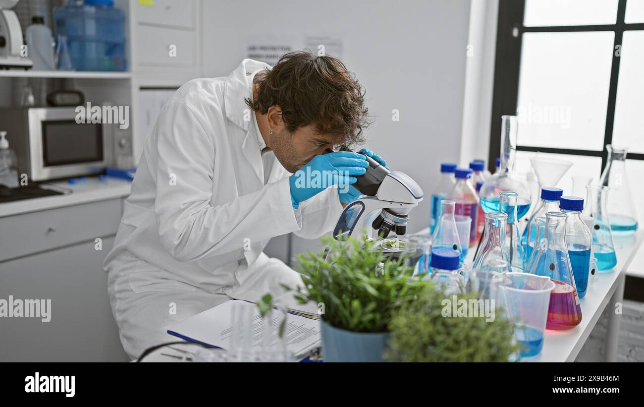 Scientist using microscope in laboratory with flasks, beakers, plants ...