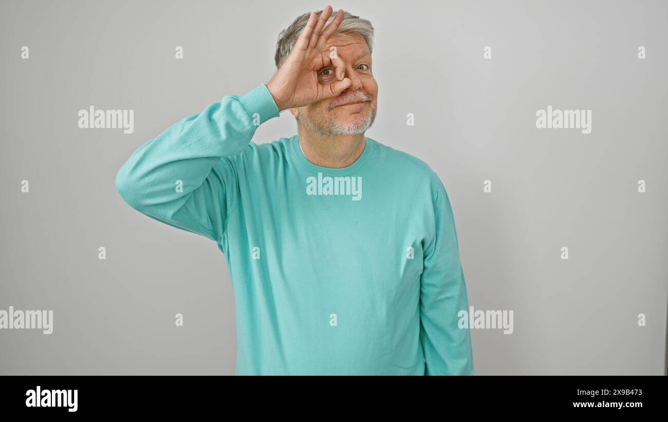 Mature grey-haired man in turquoise attire playfully gesturing with ...