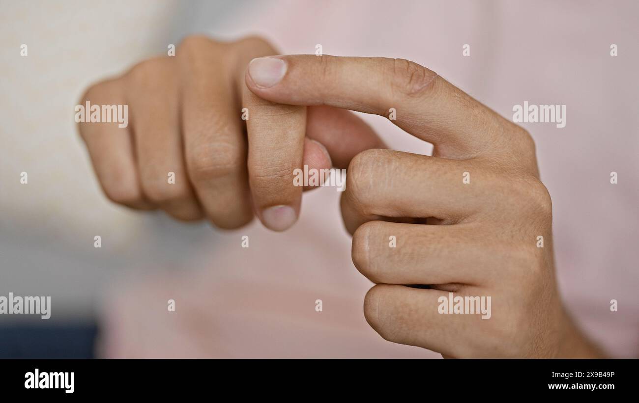 Close-up of a young man's hands using sign language indoor, with a ...