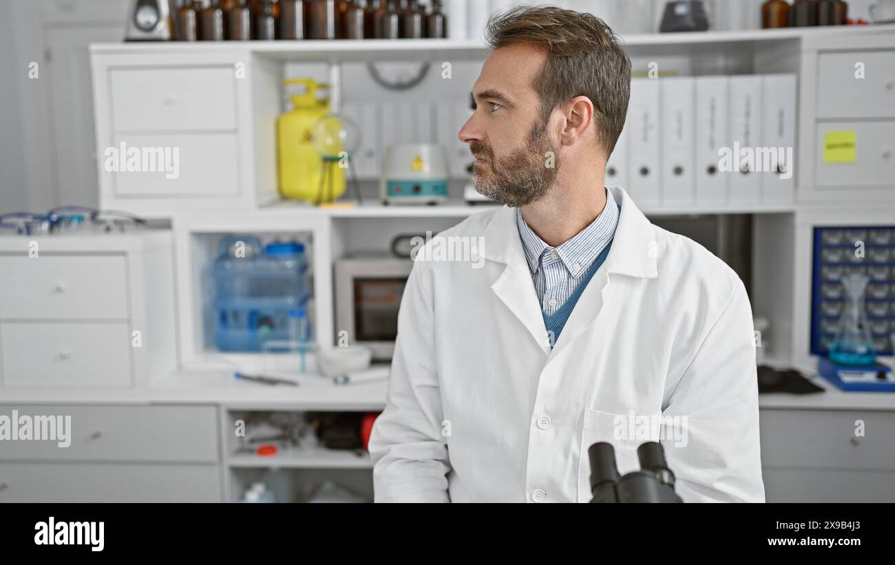 Bearded man in labcoat standing thoughtfully in a modern laboratory ...