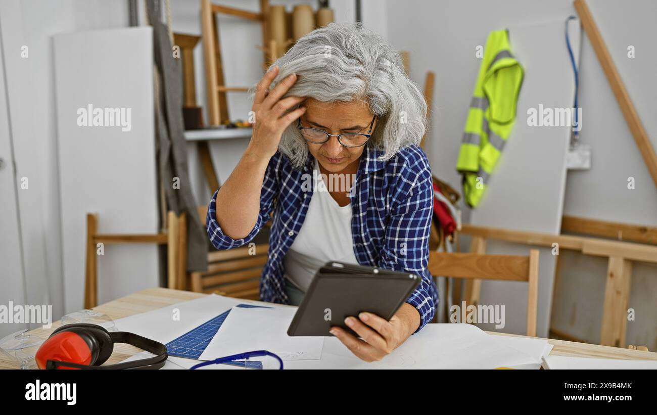 A Stressed Woman In A Workshop Looks At A Tablet With Blueprints Indicating A Carpentry 3755