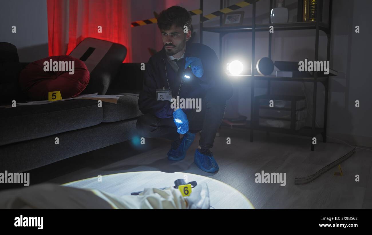 A man with a beard kneeling at a nighttime indoor crime scene ...