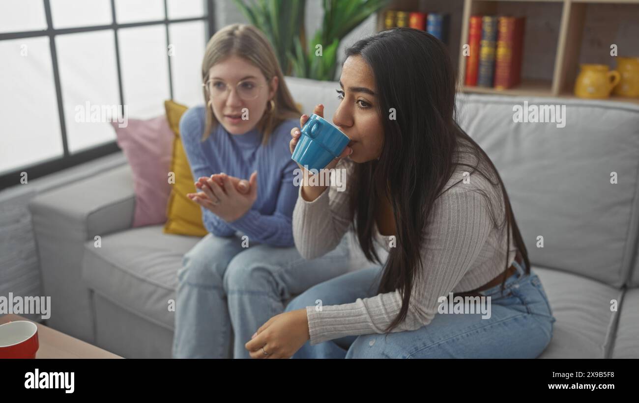 Two women conversing casually on a couch in a cozy, well-lit living ...