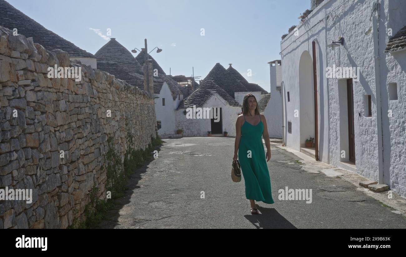 A young hispanic woman in a green dress walks along a charming street ...