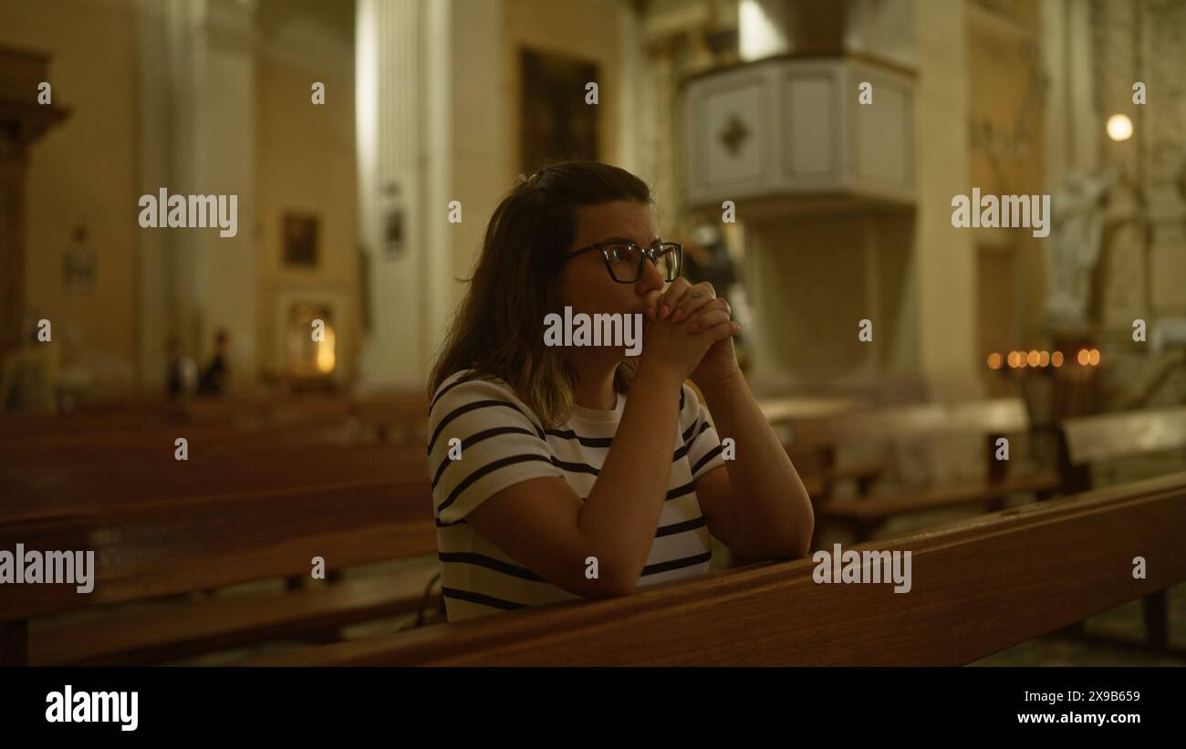 A young hispanic woman is seen praying inside a beautiful italian ...