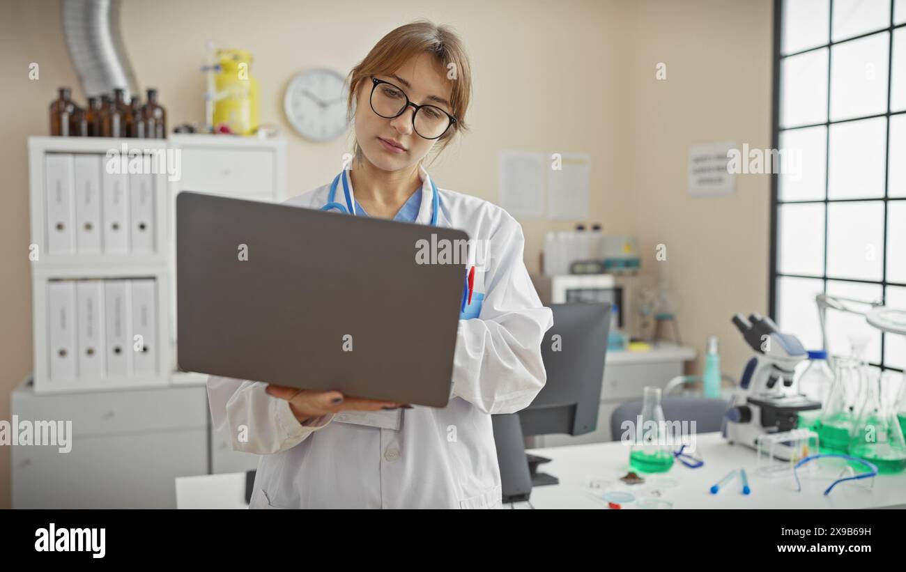 A young caucasian woman doctor examines a laptop in a well-equipped ...