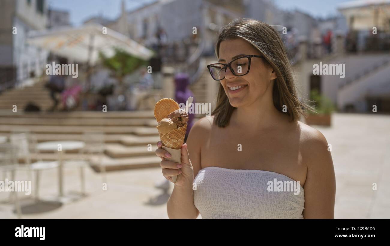 A young, hispanic woman enjoys ice cream in a waffle cone at the ...