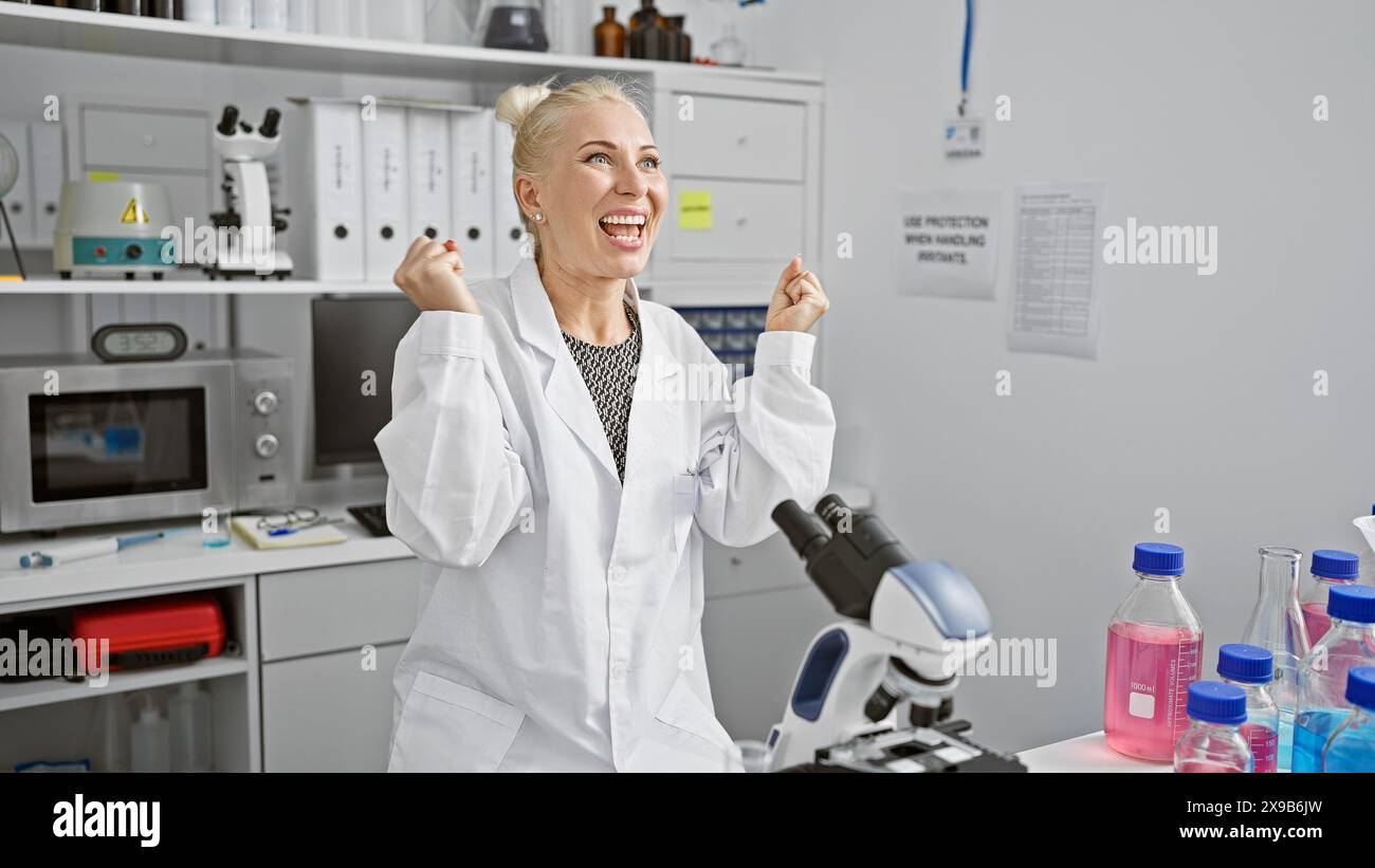 Attractive young blonde woman scientist celebrating a winning discovery ...
