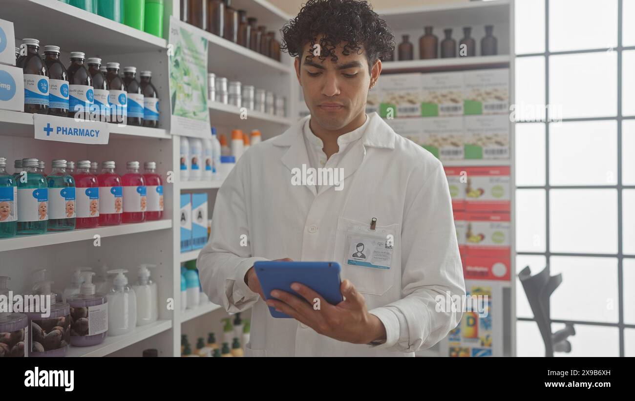 A young hispanic man dressed as a pharmacist uses a tablet indoors at a ...