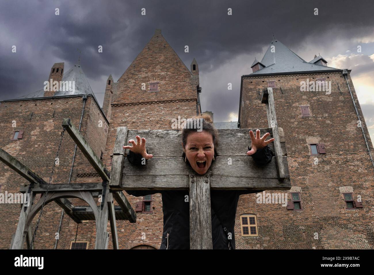 lady in stocks medieval torture device at Slot Loevestein castle fort. Historic building used by ...