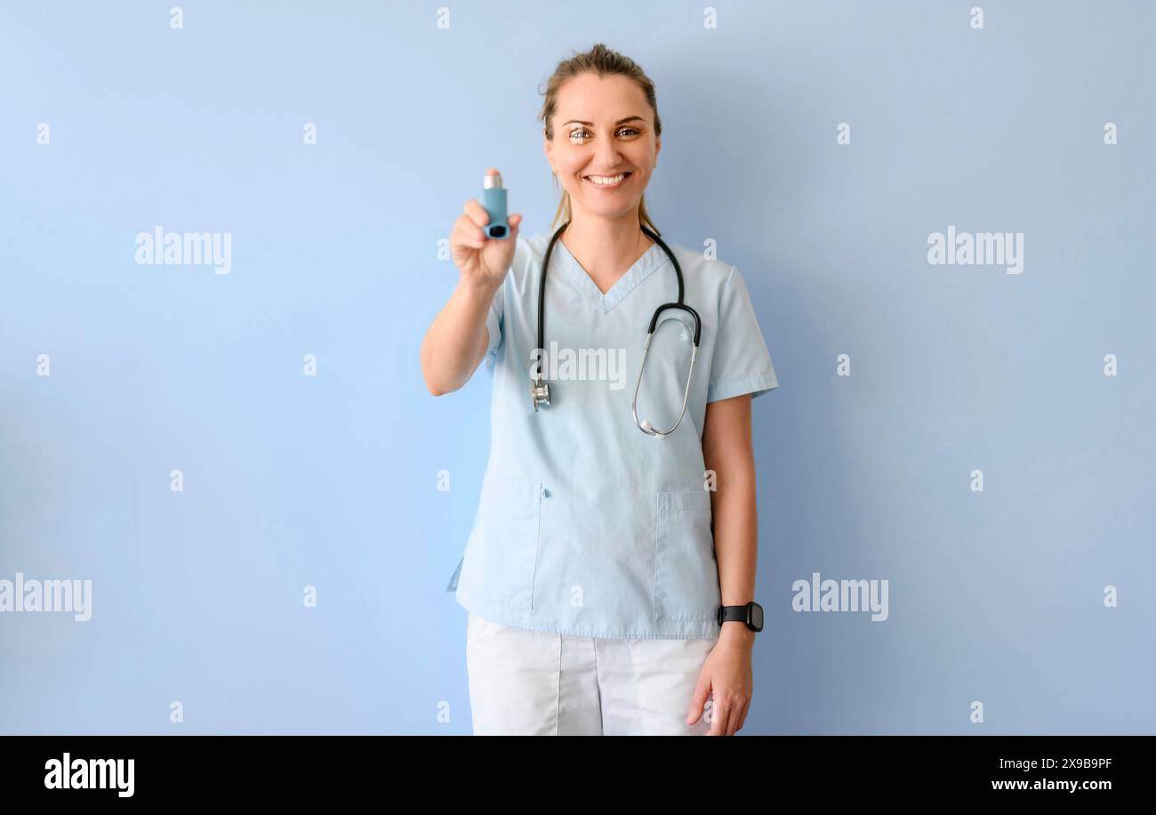 Smiling young inhalotherapy woman with stethoscope holding asthma pump ...