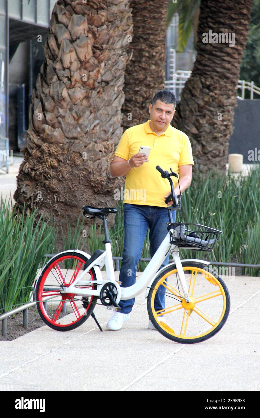 Dark-skinned Latino adult man uses a public bicycle that he pays for ...