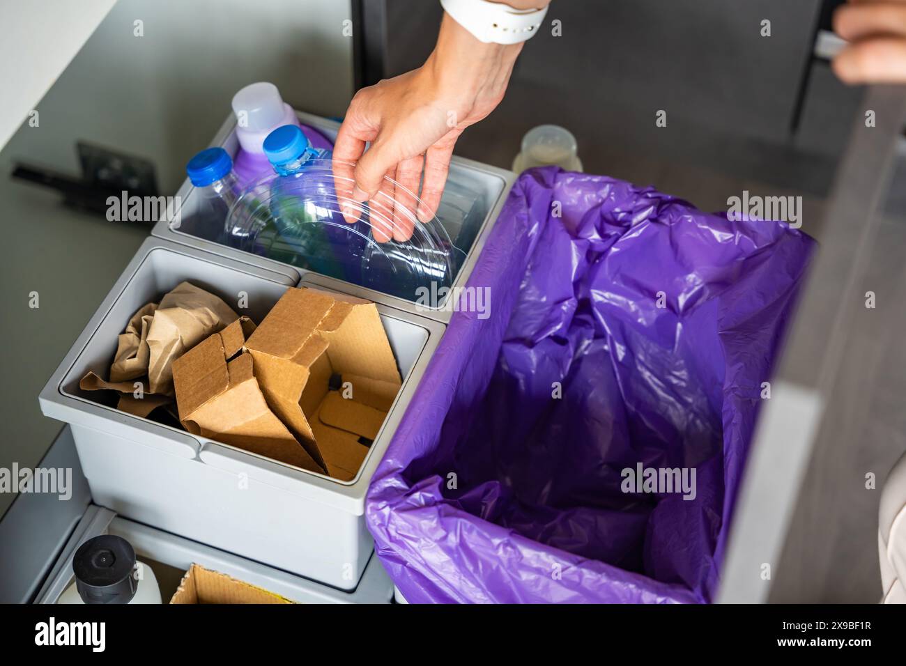 Hand of woman throwing trash into household bins for waste sorting in ...
