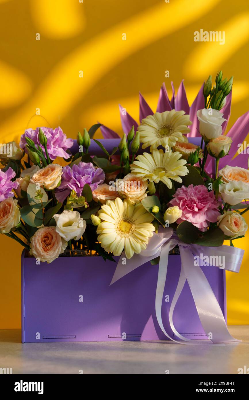 Assorted flowers arranged neatly inside a charming purple box, ready to ...