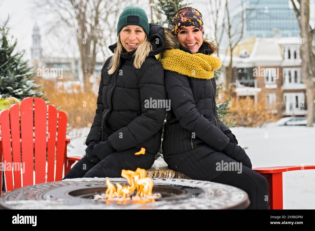 Two friends in winter coats sitting fire in forest Stock Photo - Alamy