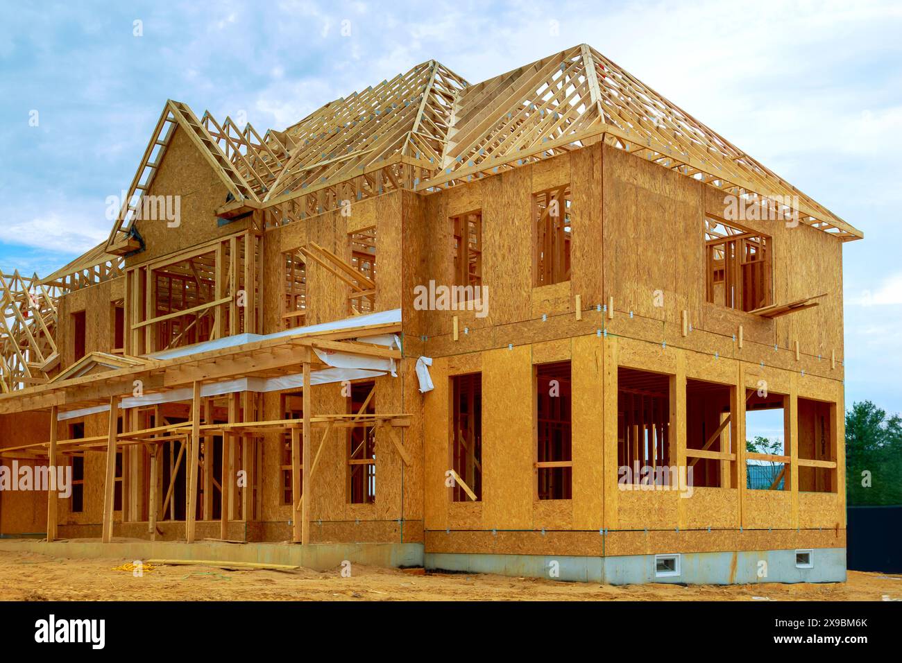 An unfinished interior of newly built house with wood framing supports ...