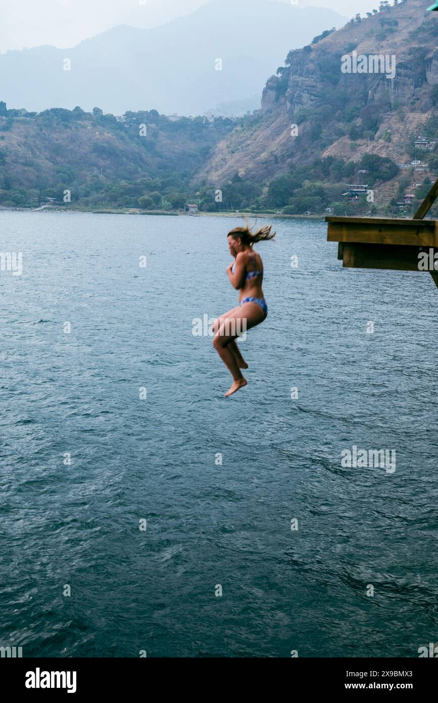 Woman jumping of a 12-meter-high cliff into the lake, Cerro Tzankujil ...