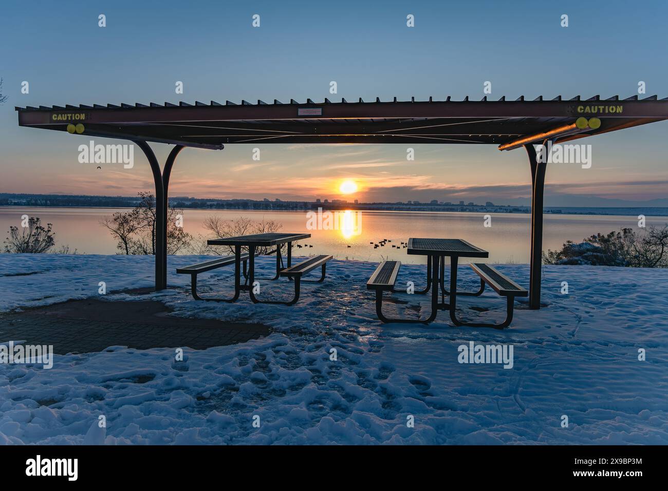 A picnic table and shelter in frames the setting sun at Cherry Creek ...