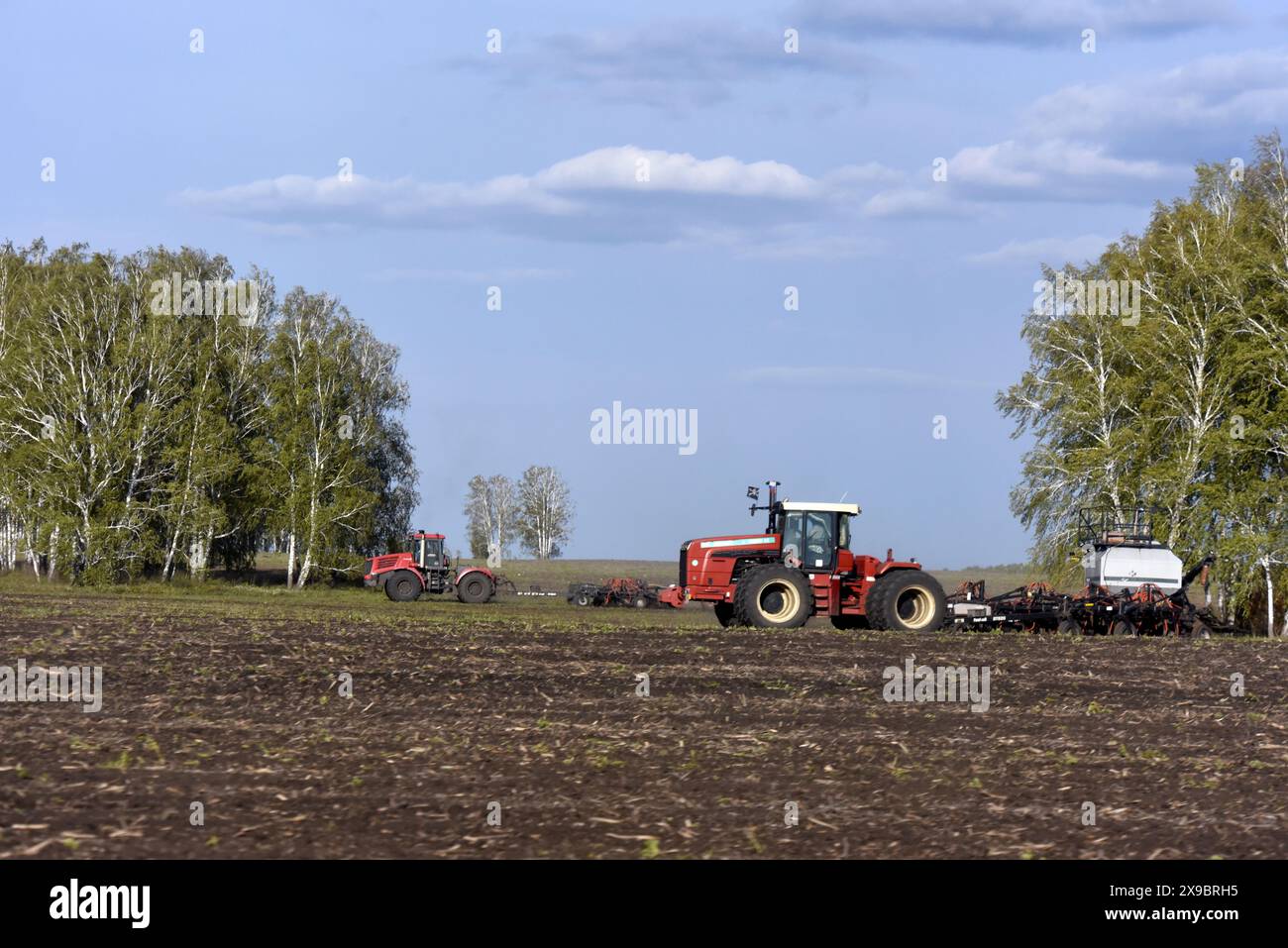 Agricultural machines for sowing grain in the field. Red tractors in ...