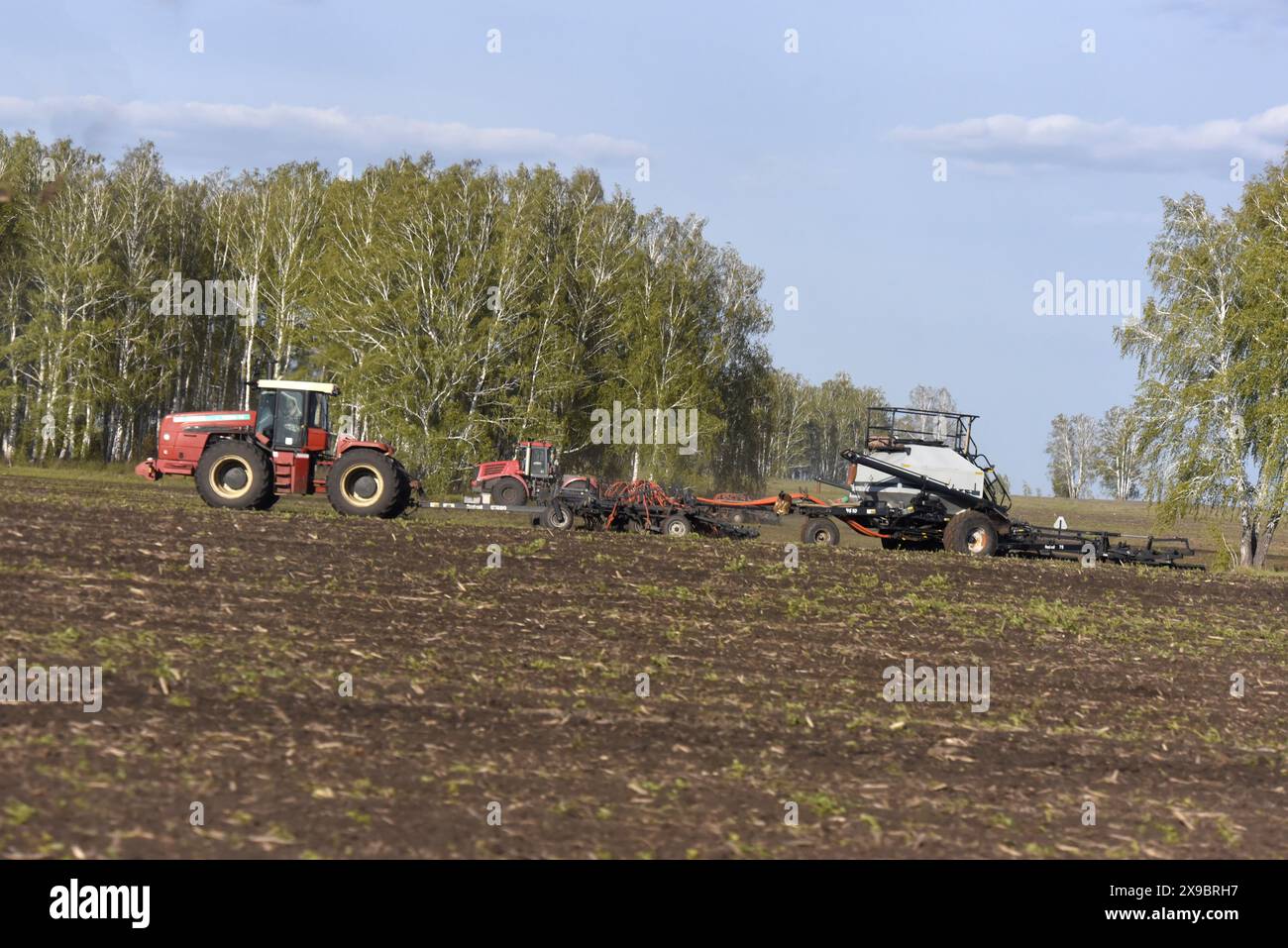 Agricultural machines for sowing grain in the field. Red tractors in ...