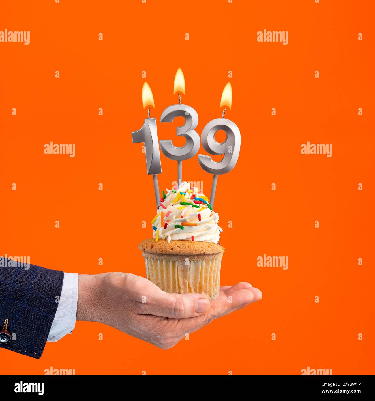 Hand holding birthday cupcake with number 139 candle - background ...