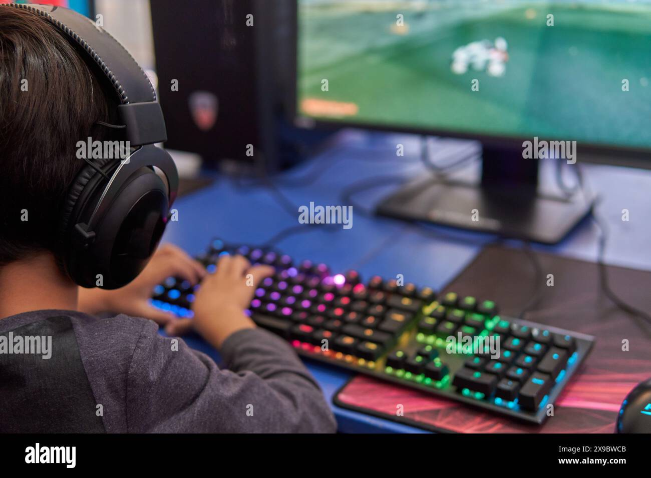 child with back headphones playing video games on a computer with a ...