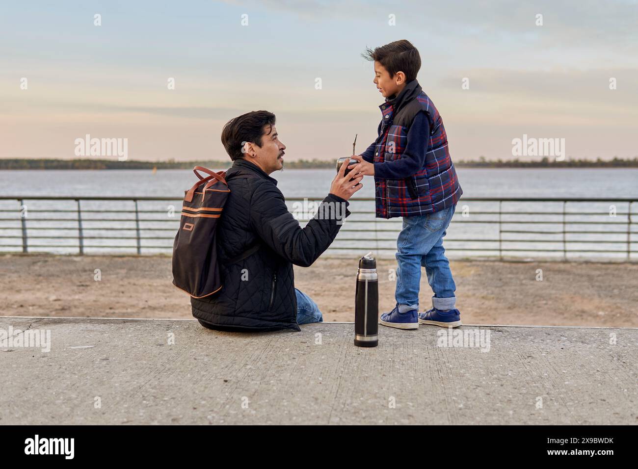 portrait of Latin father and son in profile drinking mate with the ...