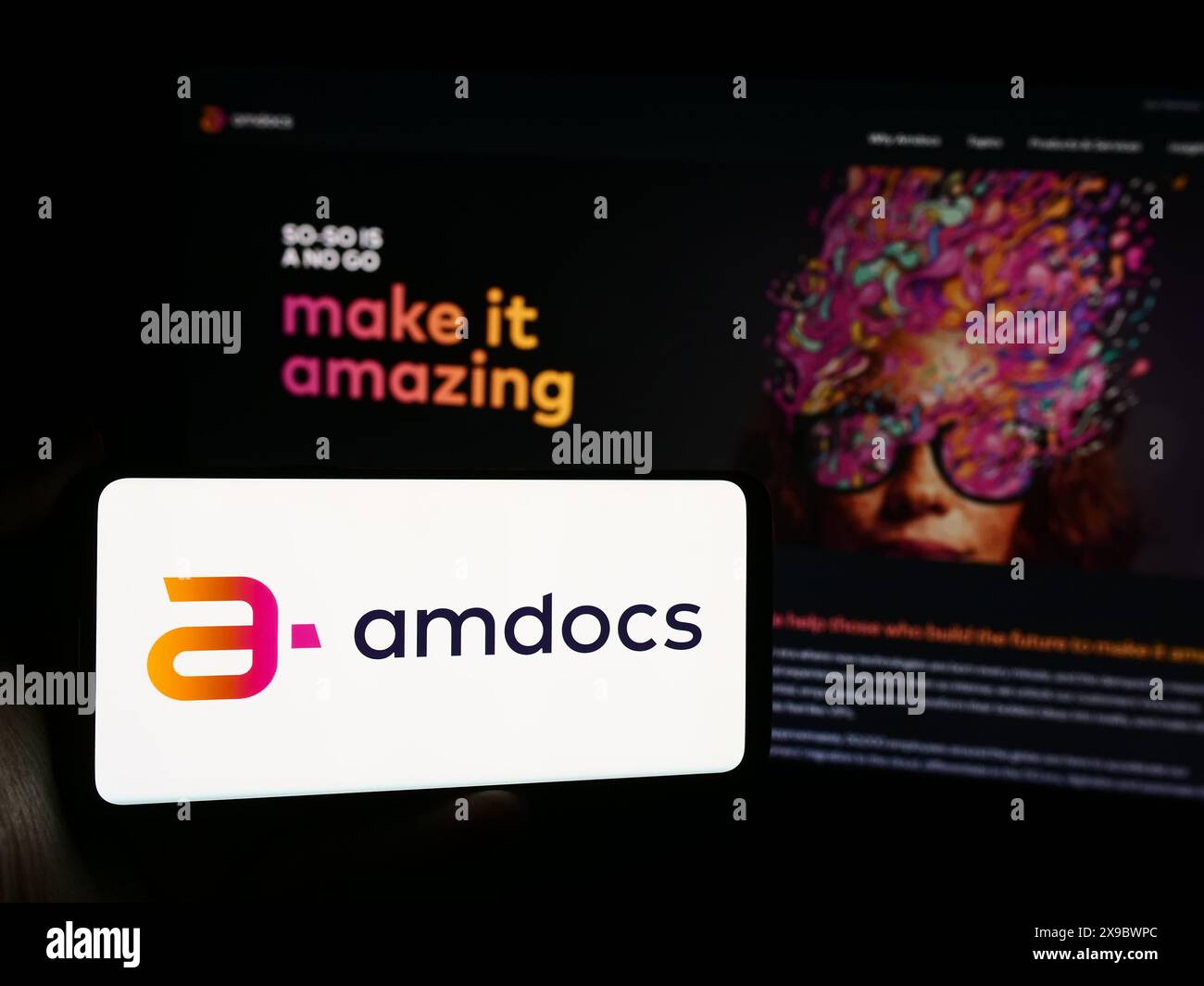 Person holding mobile phone with logo of Israeli telecom technology company Amdocs Limited in ...