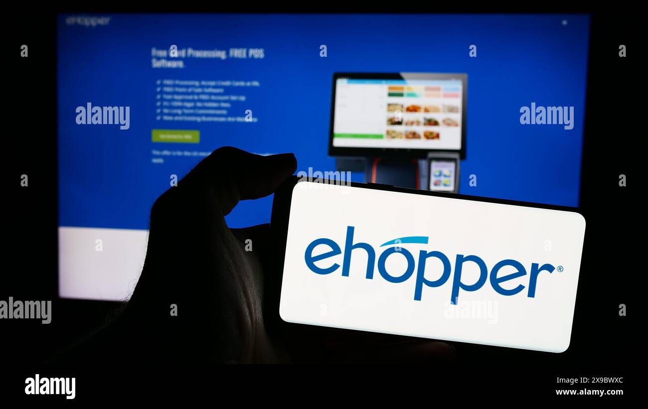 Person holding mobile phone with logo of US point of sale systems ...