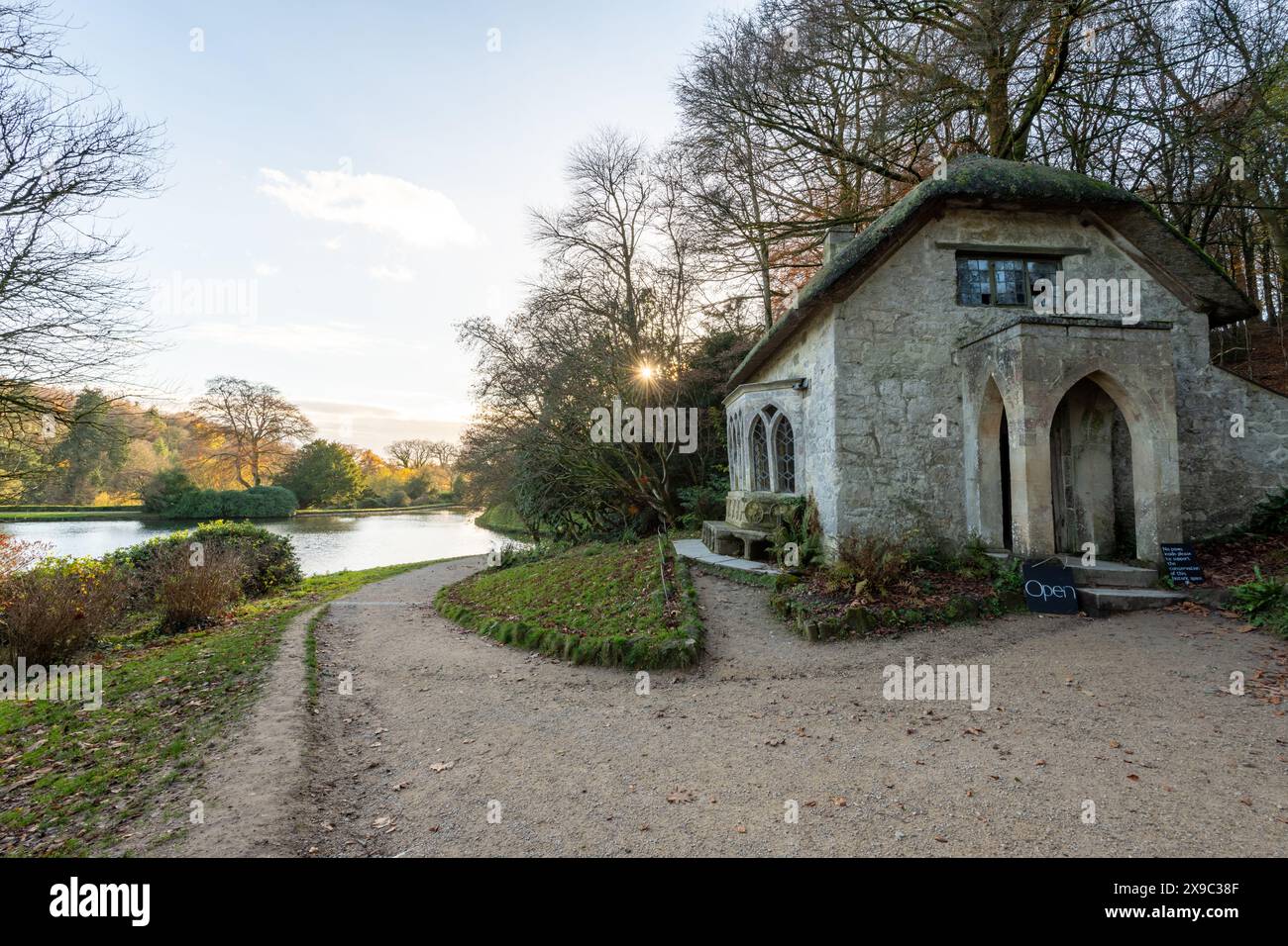 The sun setting behind the Gothic Cottage at Stourhead Gardens in ...