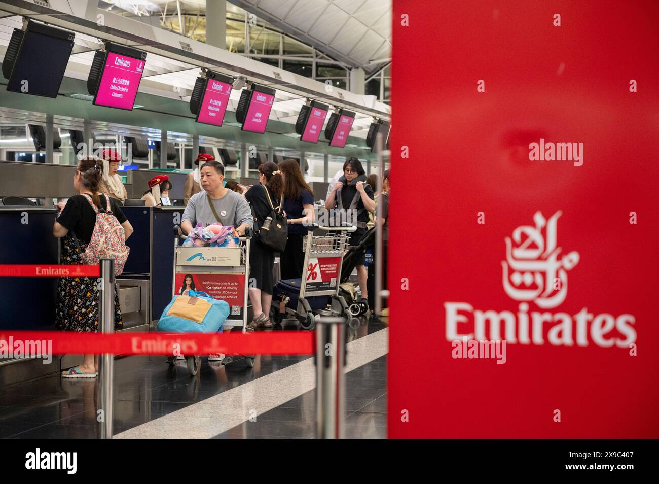 Flight passengers of Emirates Airlines go through the check-in process ...
