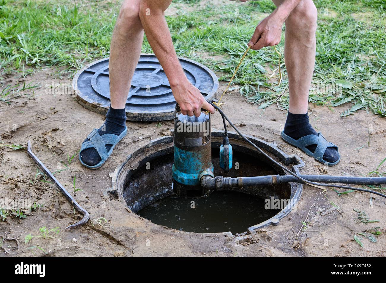 Septic tank maintenance, worker uses submersible waste water pump to ...
