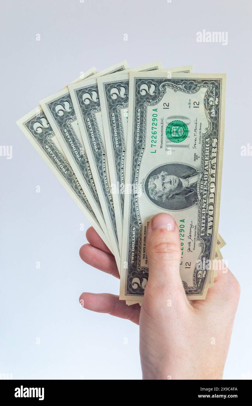 5 Two US dollars held in his right hand Stock Photo - Alamy