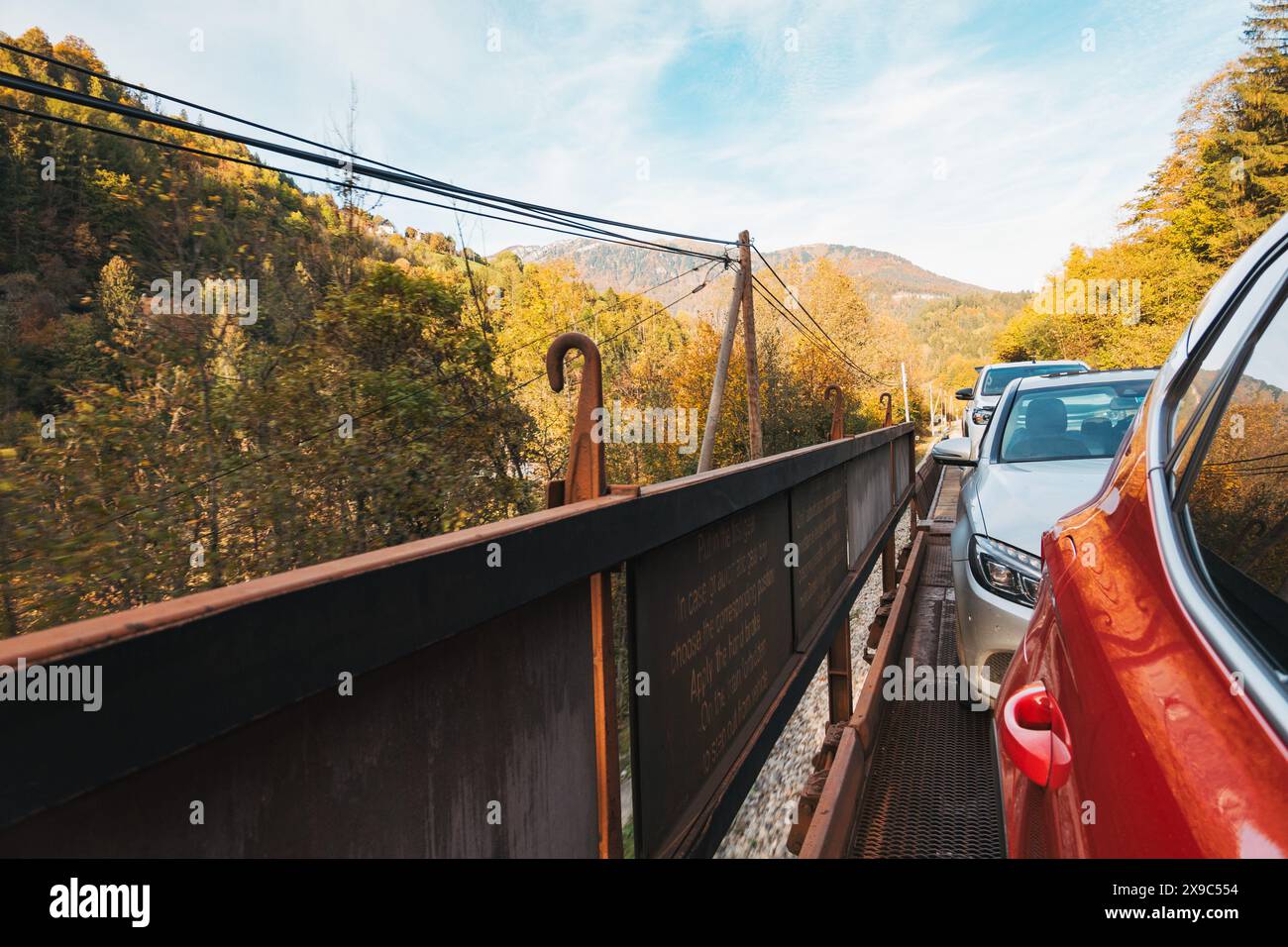 cars traveling on a motorail flatbed rail carriage down a mountain in ...