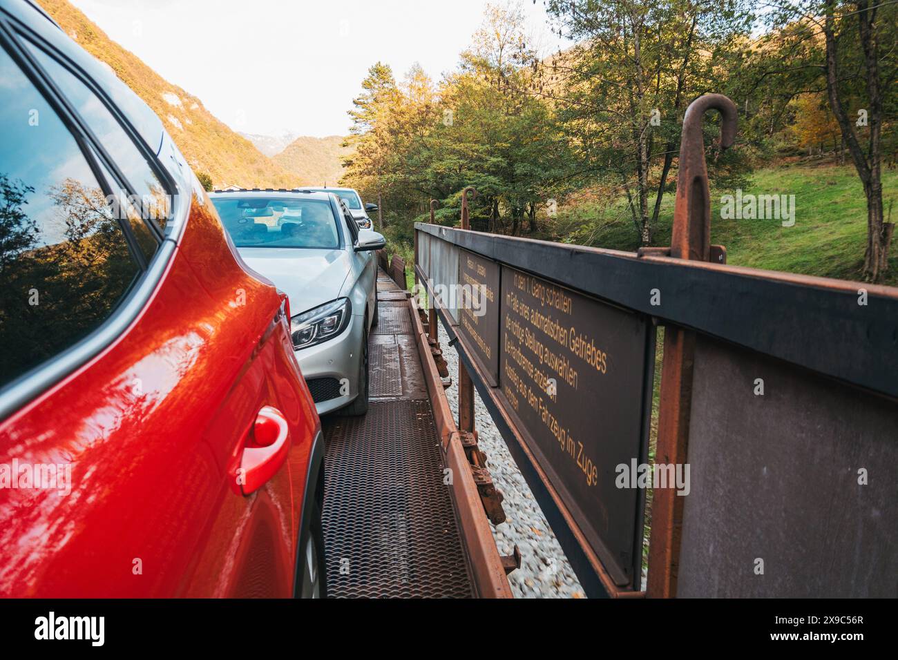 cars traveling on a motorail flatbed rail carriage down a mountain in ...