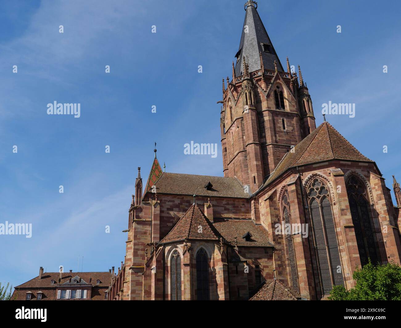 Gothic church with high towers under a blue sky, historic house fronts ...