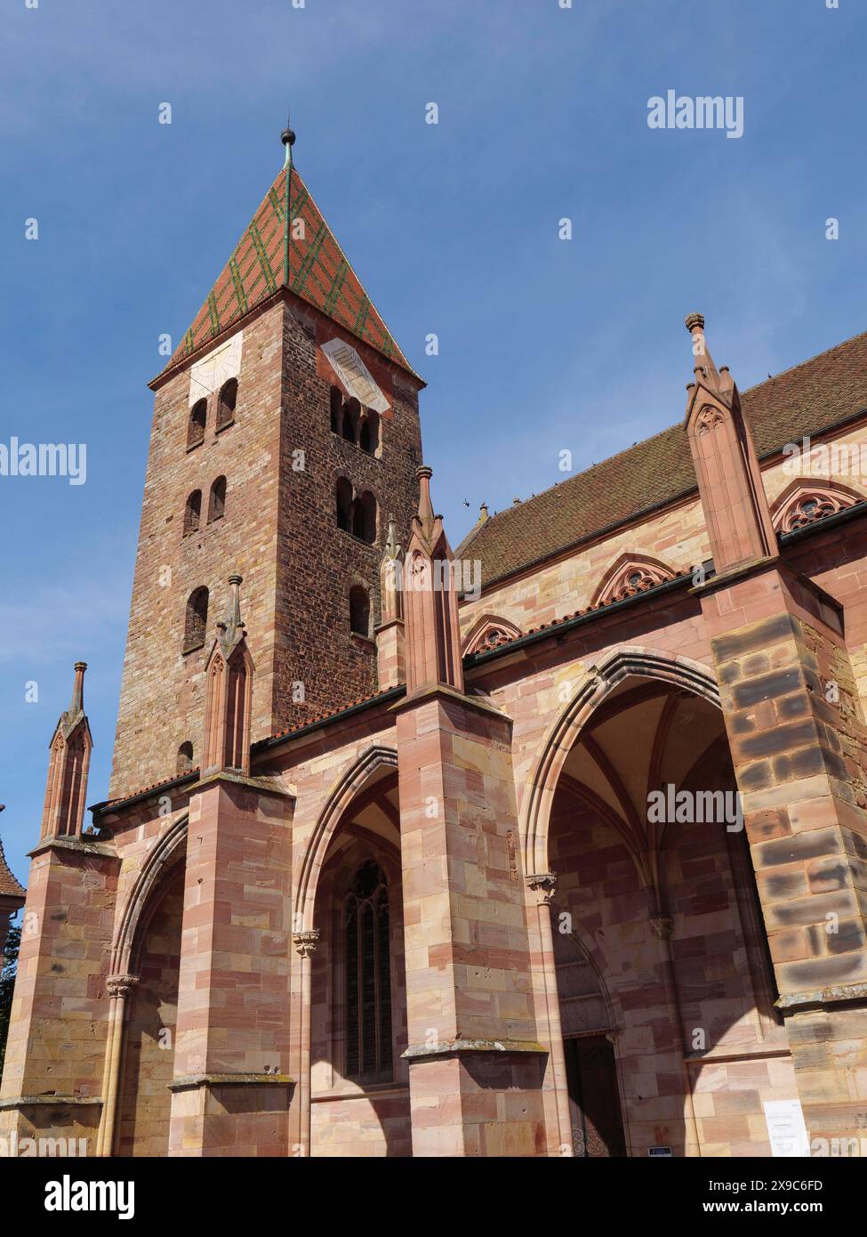 Towering Gothic church tower made of bricks and stones against a clear ...